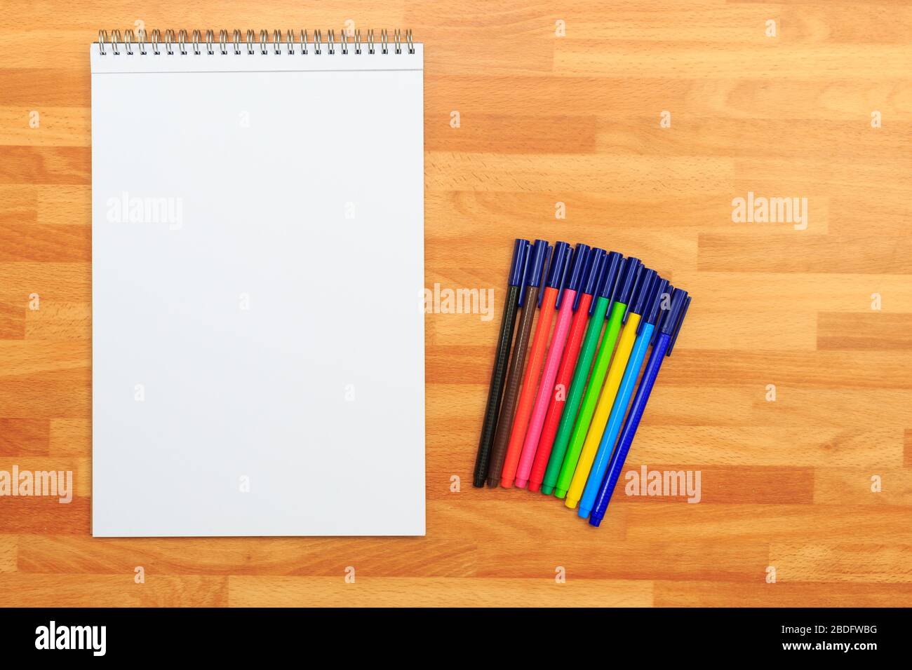 Looking down on a group of colour felt pens and a white drawing pad on ...