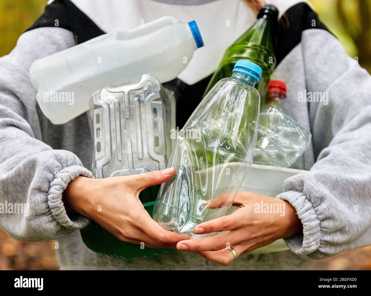 Woman holding armful of various used plastic items Stock Photo - Alamy