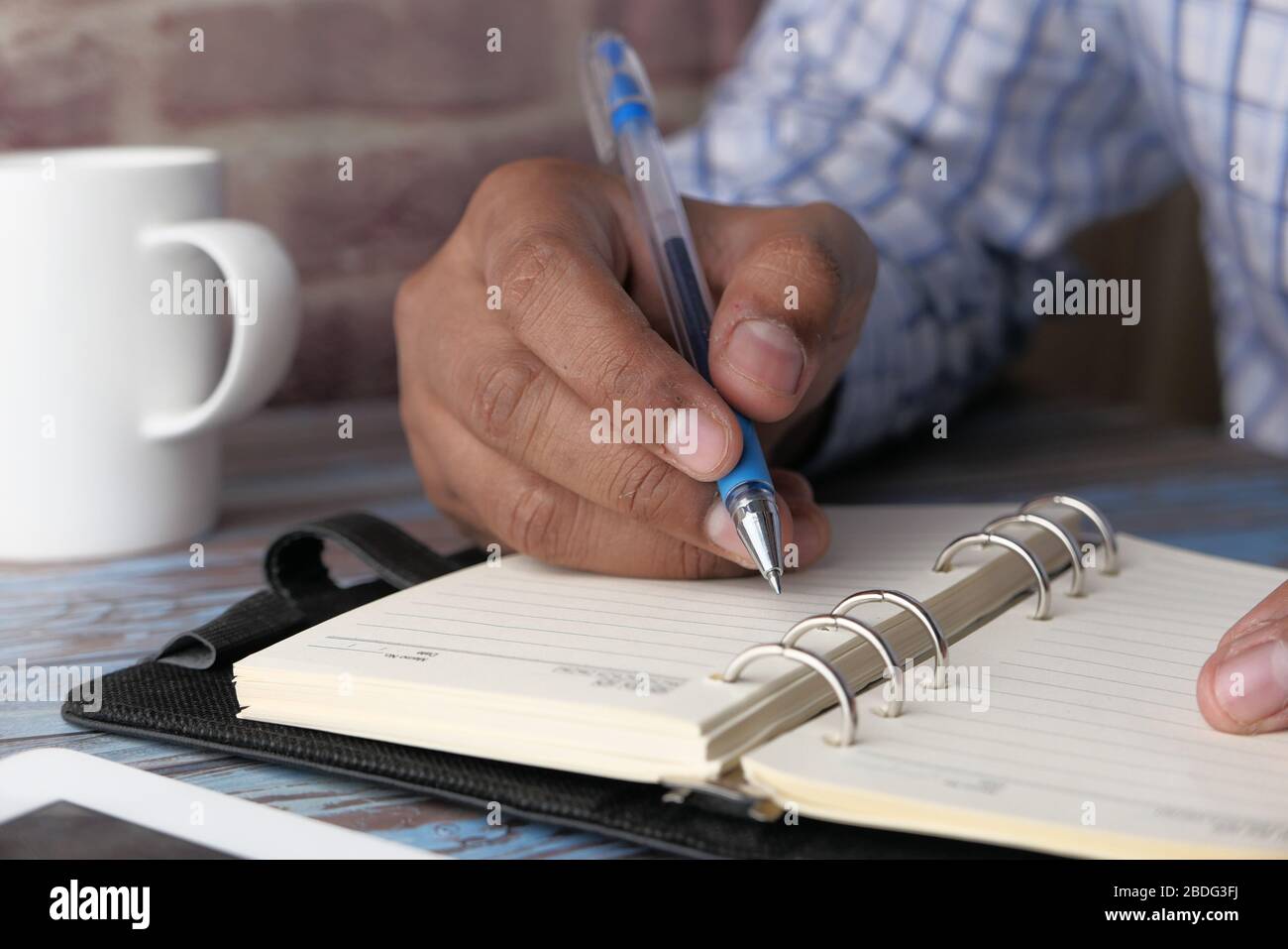 young man writing on notepad on office desk Stock Photo - Alamy