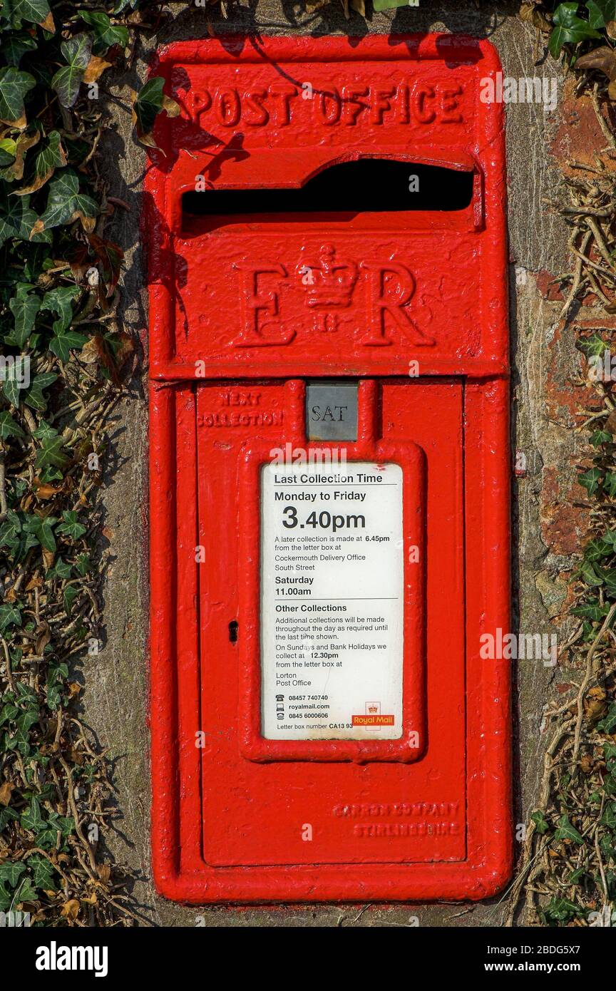 Red post box built into a wall, surrounded by Ivy in rural Cumbria, UK ...