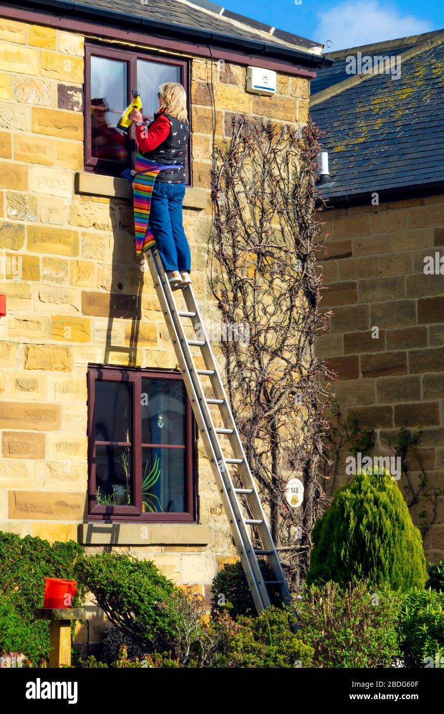 White woman on a tall ladder cleaning house windows on an upper floor Stock Photo - Alamy