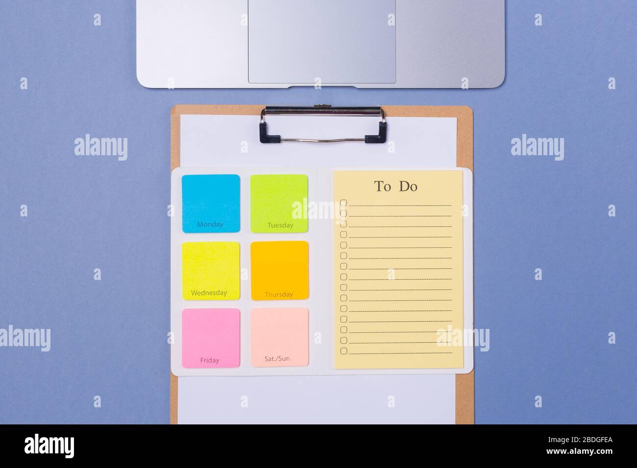 Top view of Blank To do list for the week and laptop on light purple ...