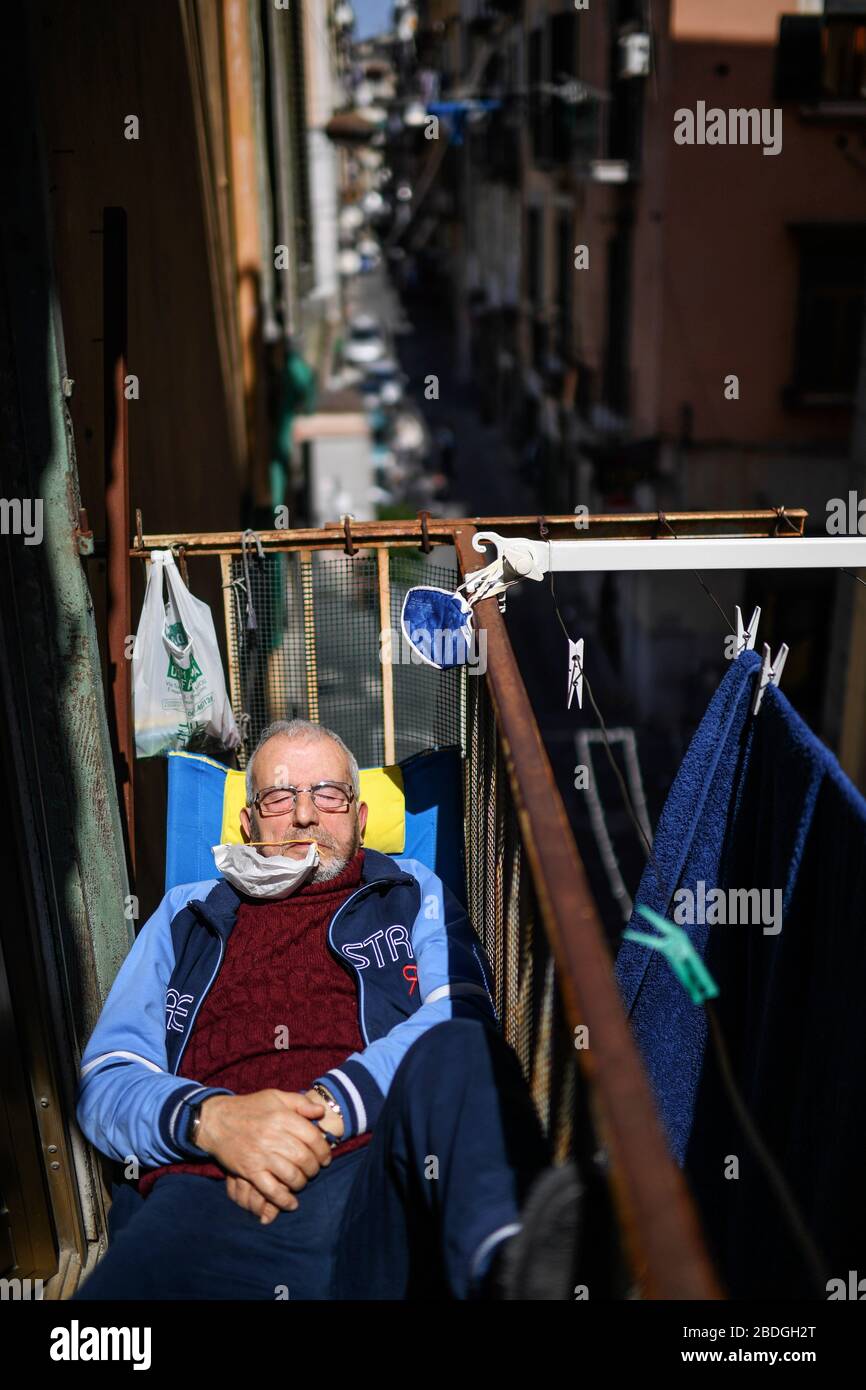 Naples, Italy. 08th Apr, 2020. A man is resting in the sun on balcony ...