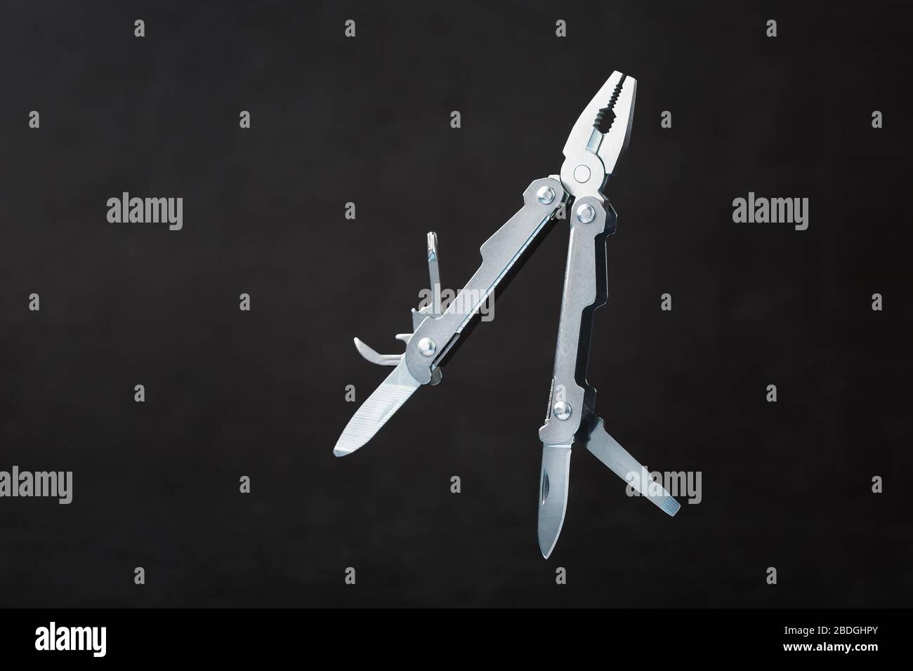 Multi-functional tool on a black textural background Stock Photo - Alamy