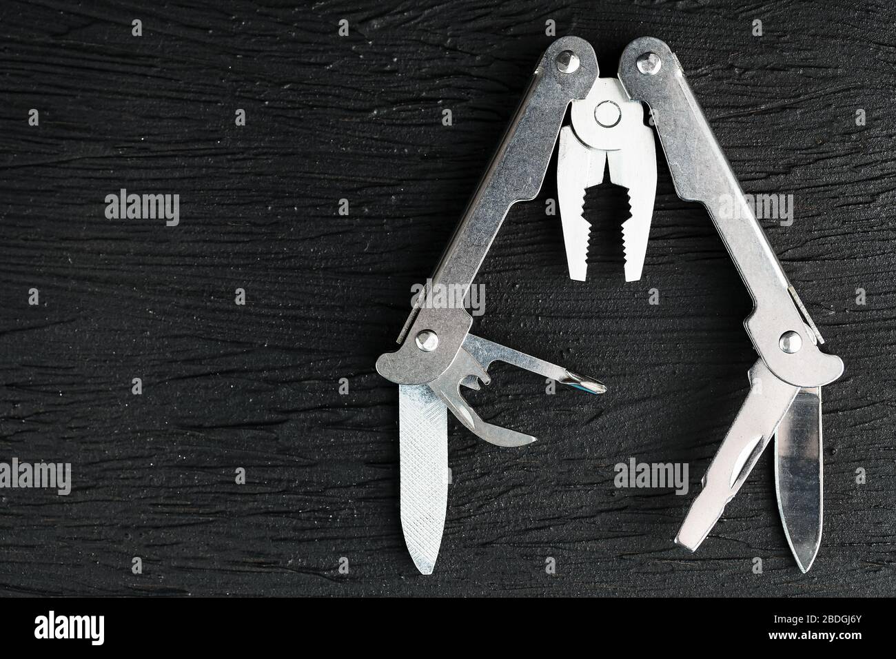 Multi-functional tool on a black textural background Stock Photo - Alamy