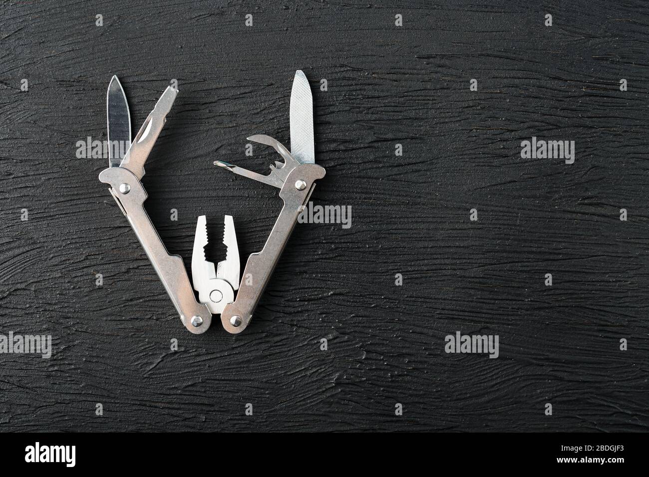 Multi-functional tool on a black textural background Stock Photo - Alamy