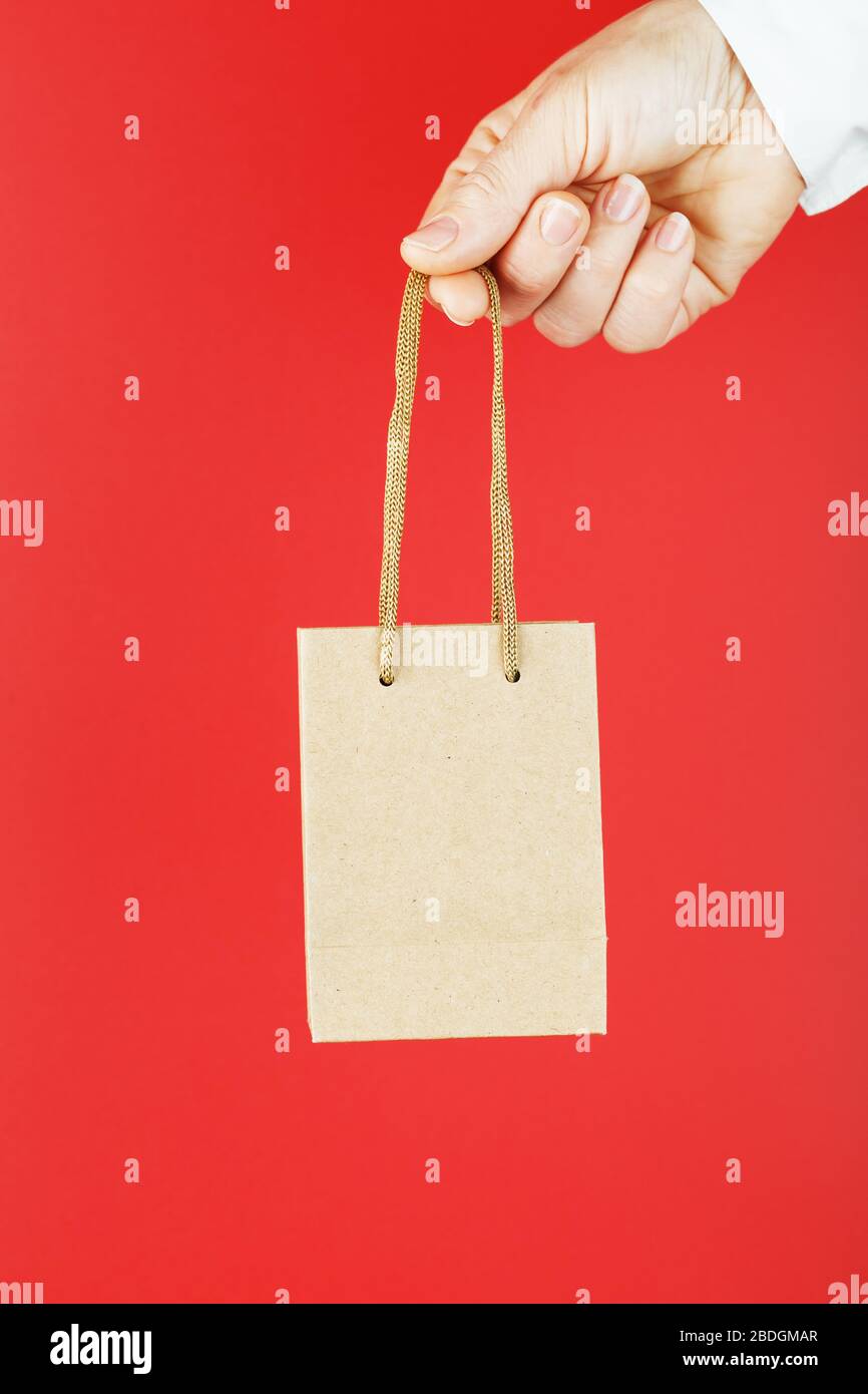 Brown paper bag at arm's length, on a red background Stock Photo - Alamy