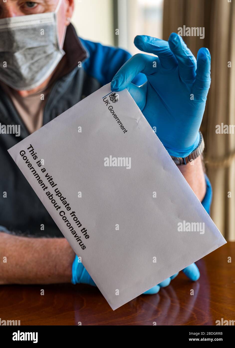 Man wearing surgical gloves and face mask with HM Government letter ...