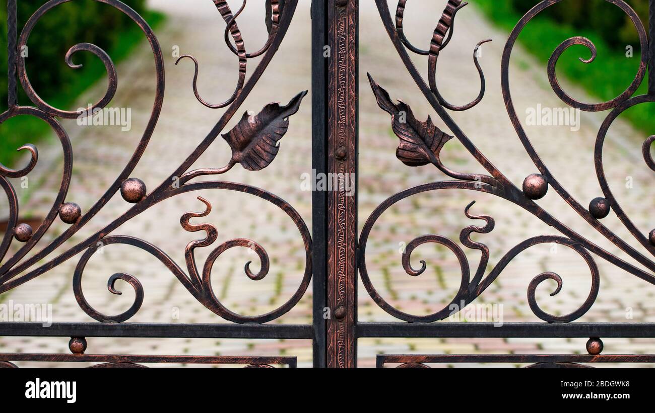 A closed forged metal gate looking onto a garden path Stock Photo - Alamy