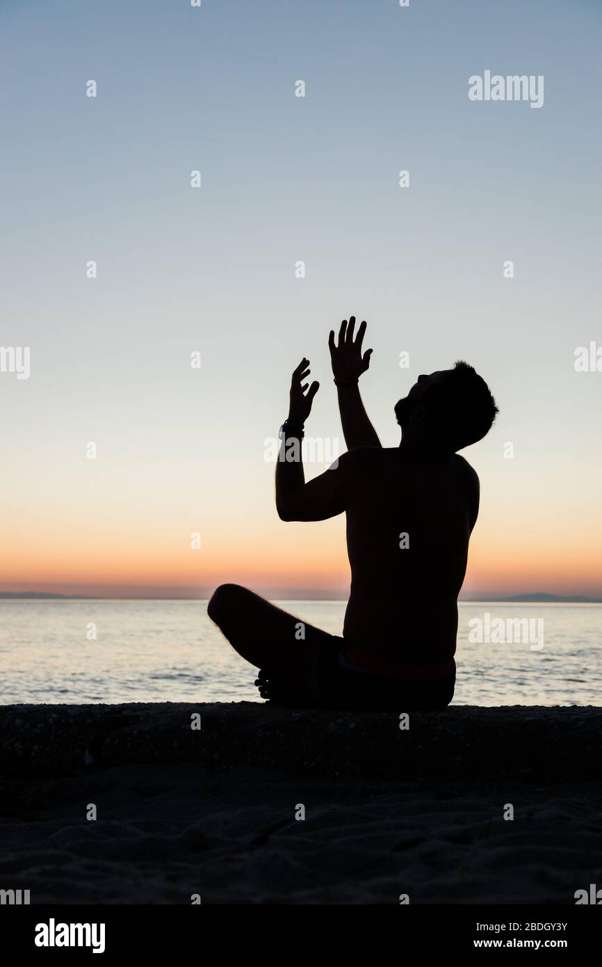 Silhouette of a man praying to God on the beach in sunset Stock Photo ...
