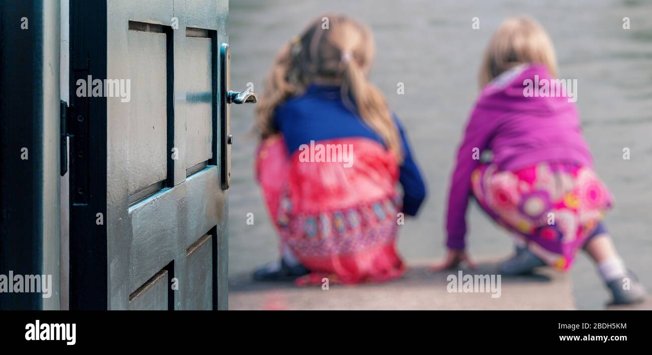 Opened door concept with two young crouching children girls playing by ...