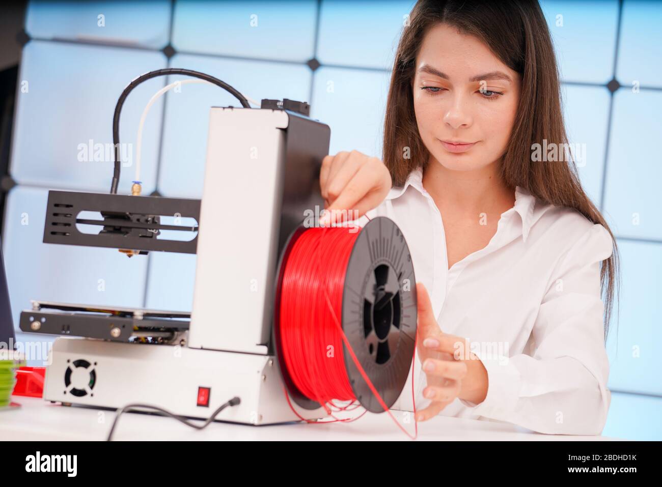 Young female designer working on a prototype device on a 3D printer ...
