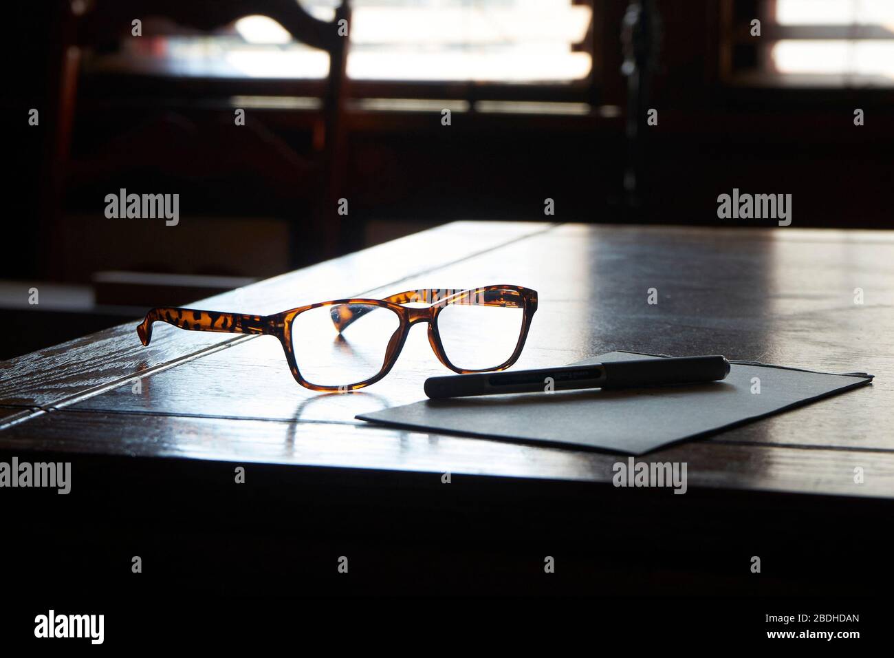 Reading glasses on desk with pen and paper Stock Photo - Alamy