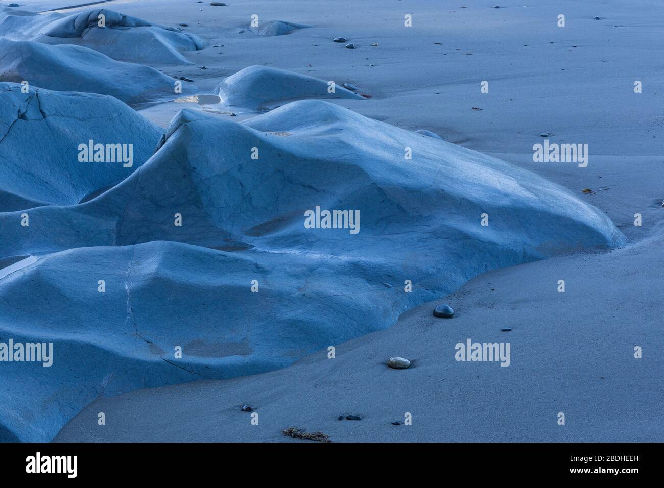Sandstone rocks, carved by waves and tides, blue in shade light, on ...