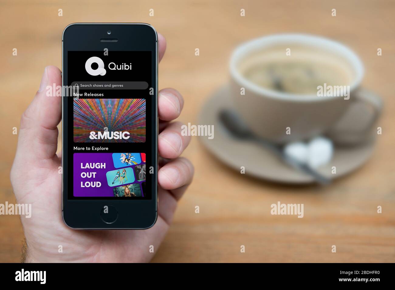 A man looks at his iPhone which displays the Quibi app (Editorial use ...