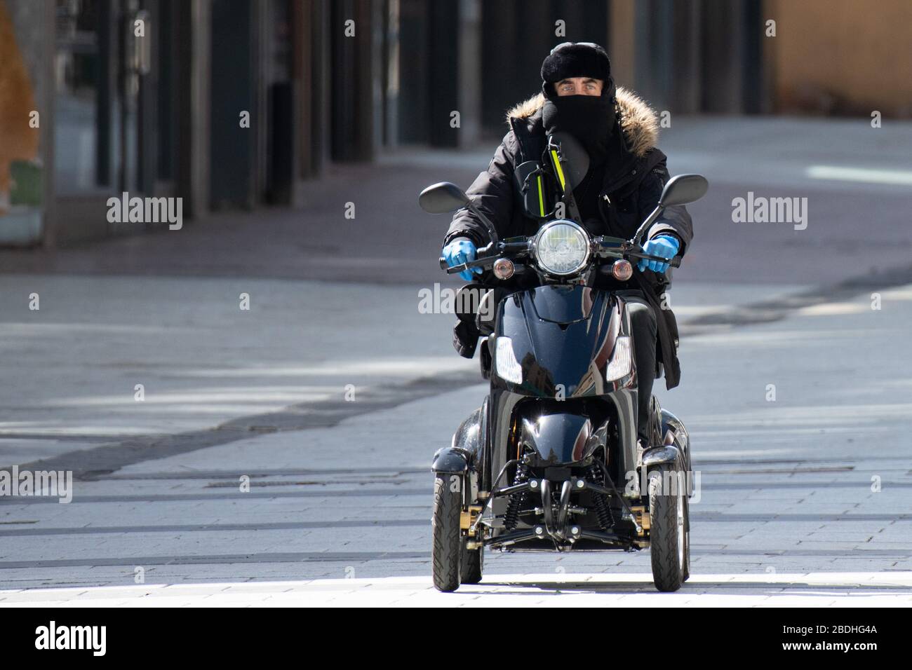 A man rides a mobility scooter in Cardiff city centre wearing a face ...