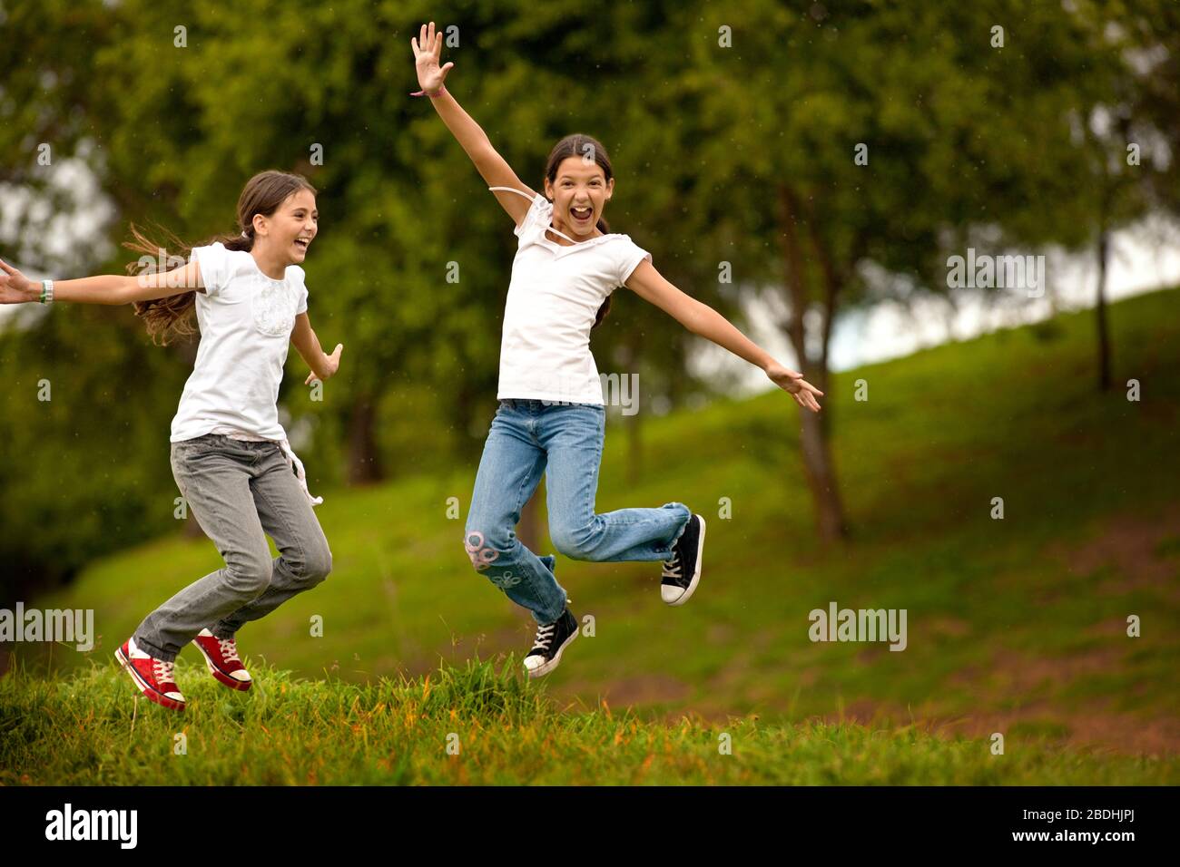 Two girls excitedly jumping in air Stock Photo - Alamy