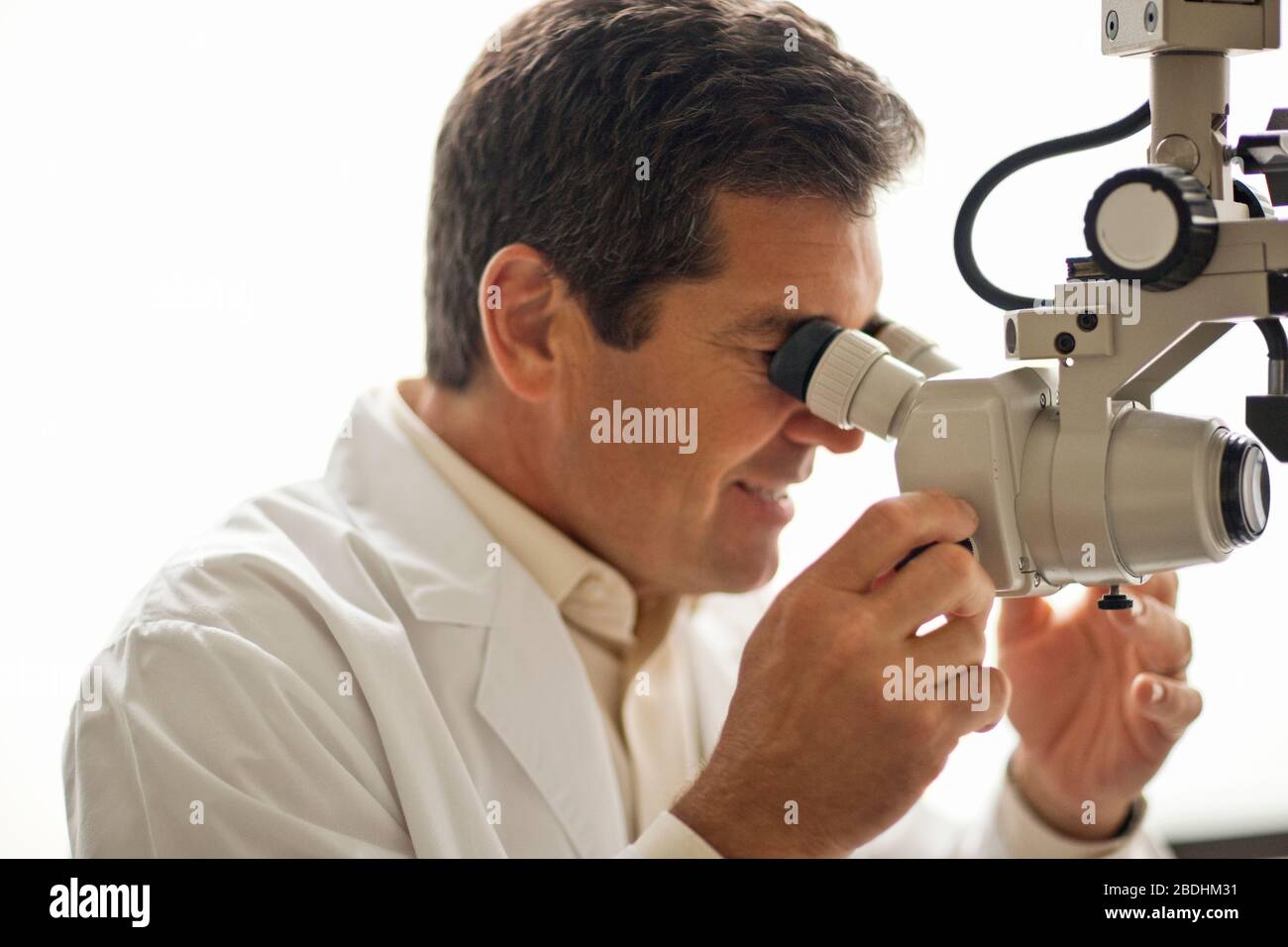 Male doctor looking at something through a microscope Stock Photo - Alamy