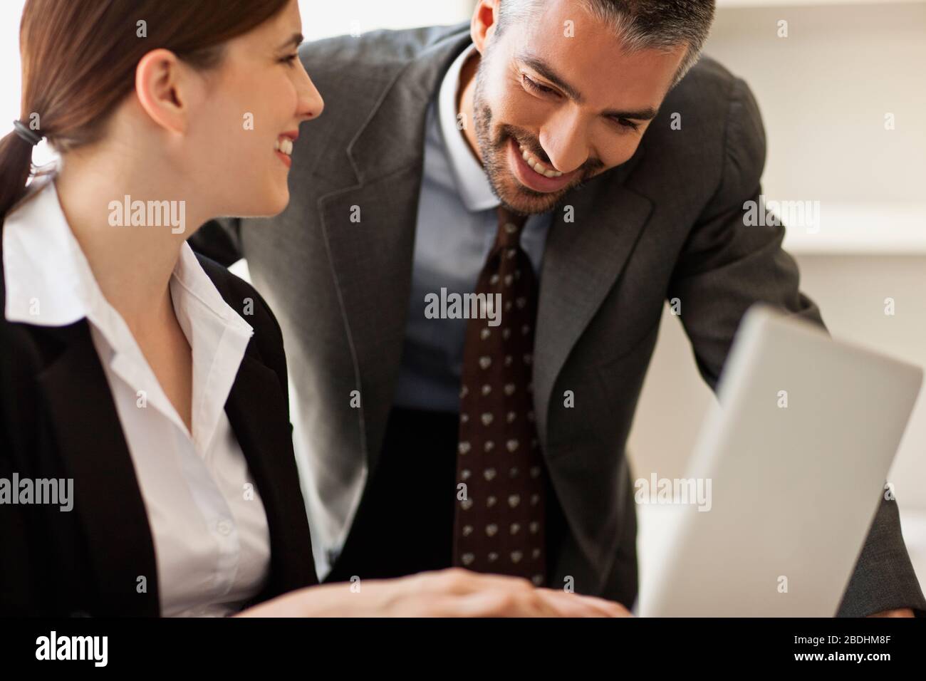 Two co-workers talking at desk Stock Photo - Alamy