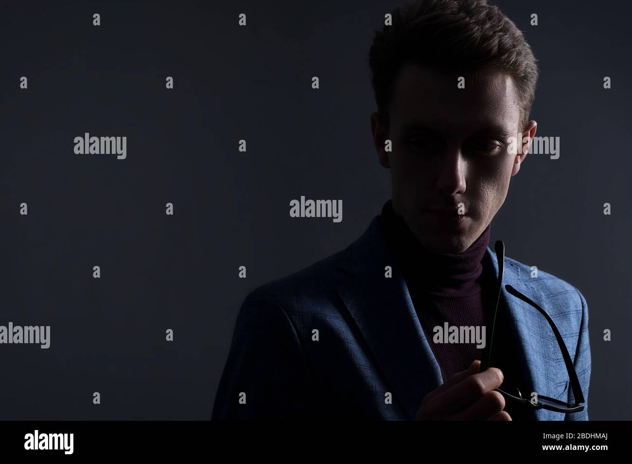 close-up dramatic portrait in dark colors of a young guy, a businessman ...