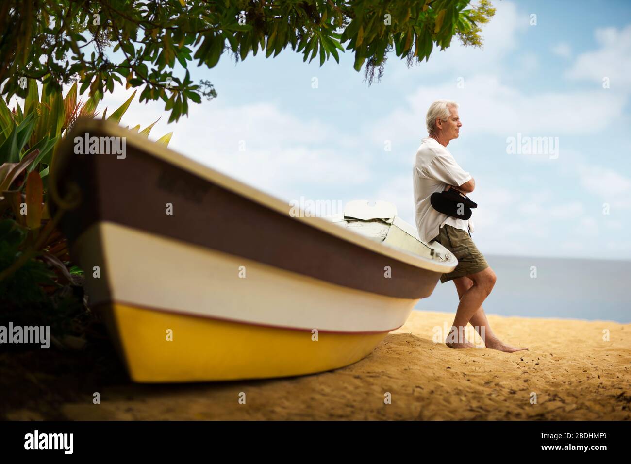 Man leans against his boat on the beach Stock Photo - Alamy