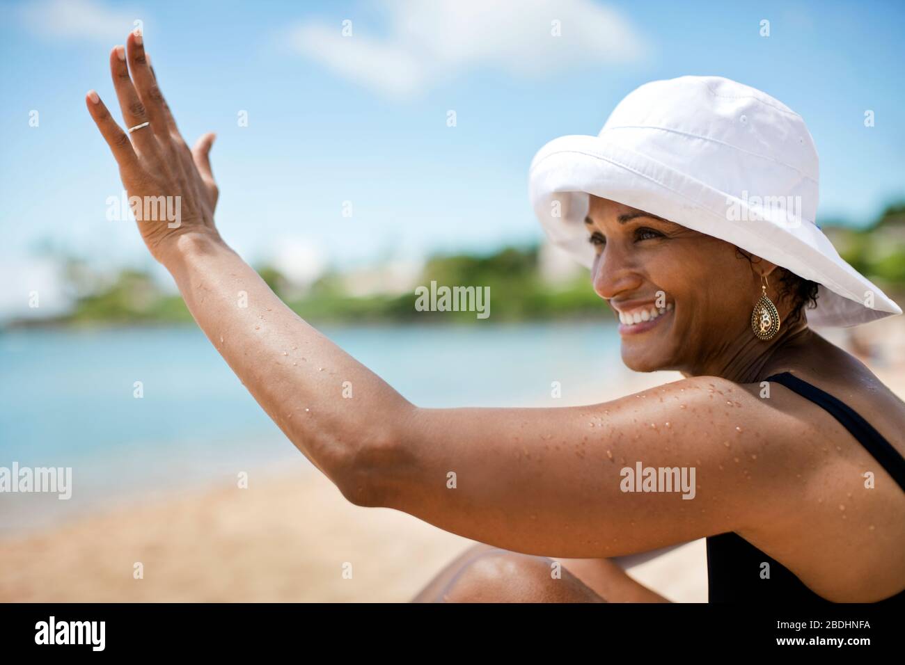 Woman waving as she sits on beach Stock Photo - Alamy