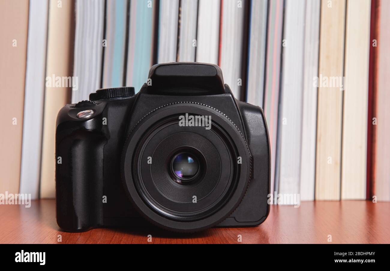 digital black camera with stacked books as background Stock Photo - Alamy