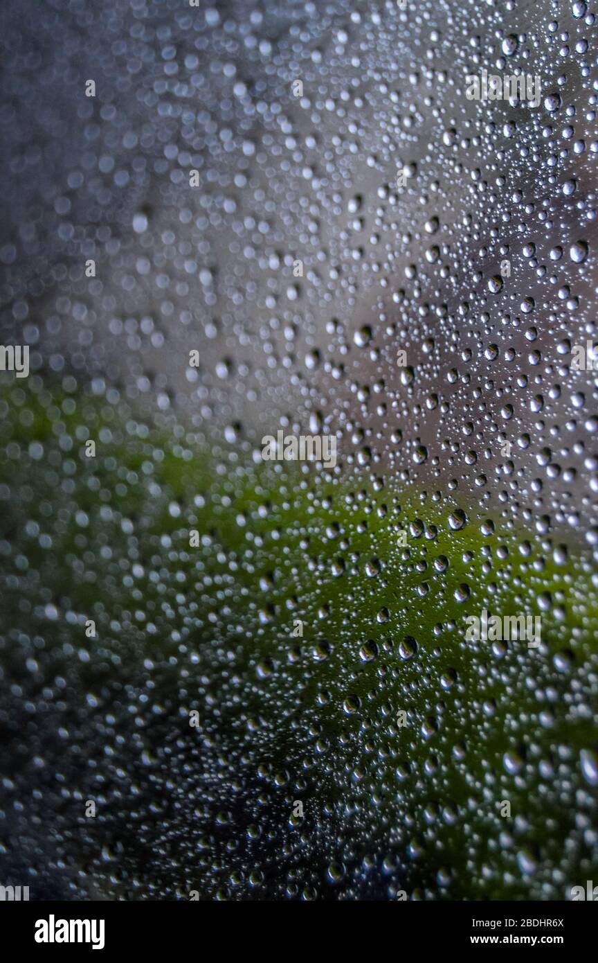 Abstract rain drops pattern on glass window of car with green ...