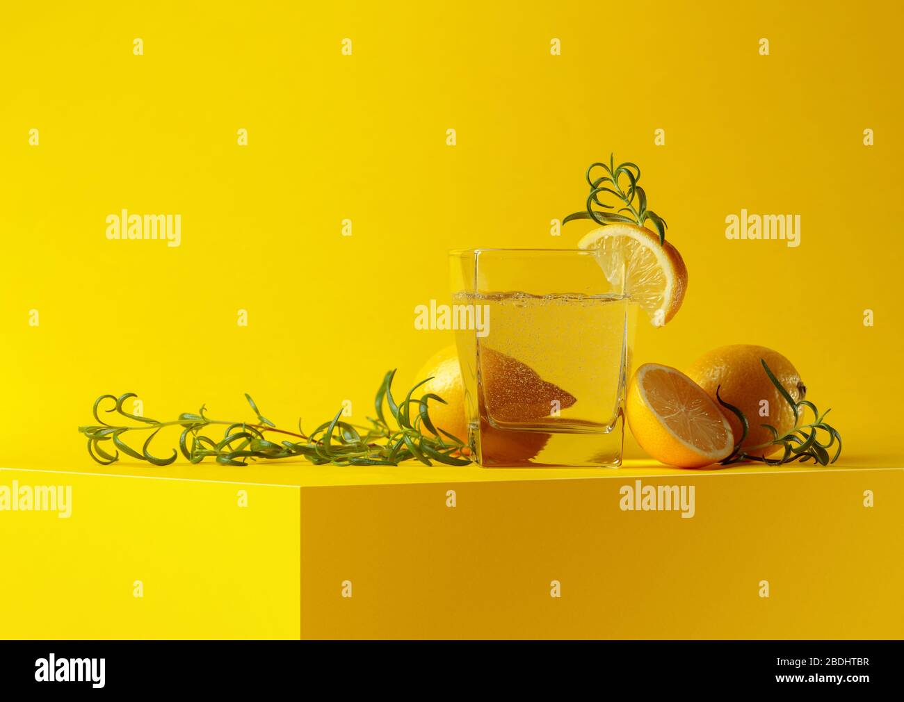 Gin tonic cocktail with lemon and rosemary on a yellow background ...