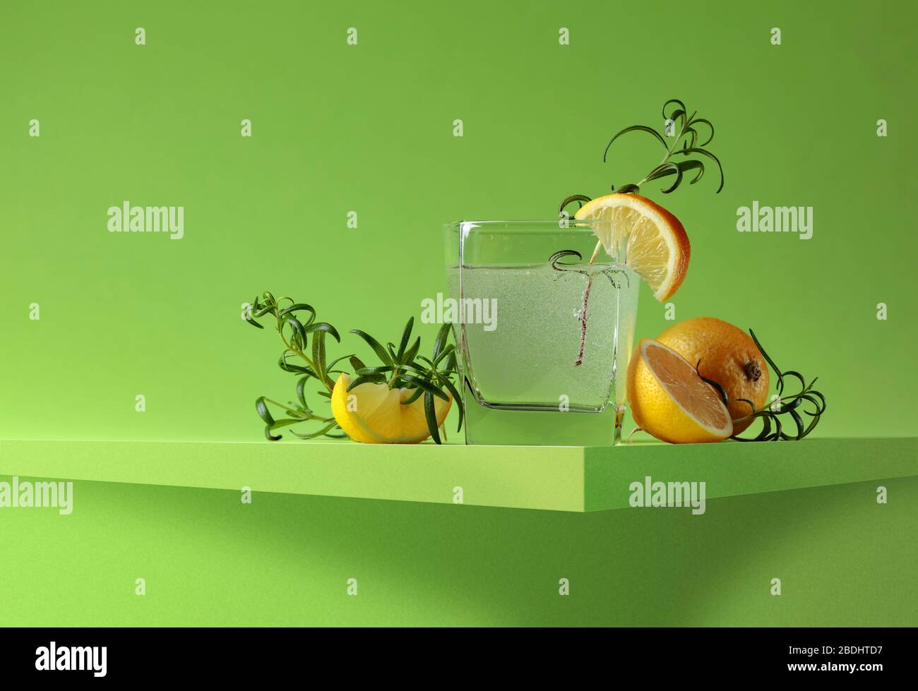 Gin tonic cocktail with lemon and rosemary on a green background ...