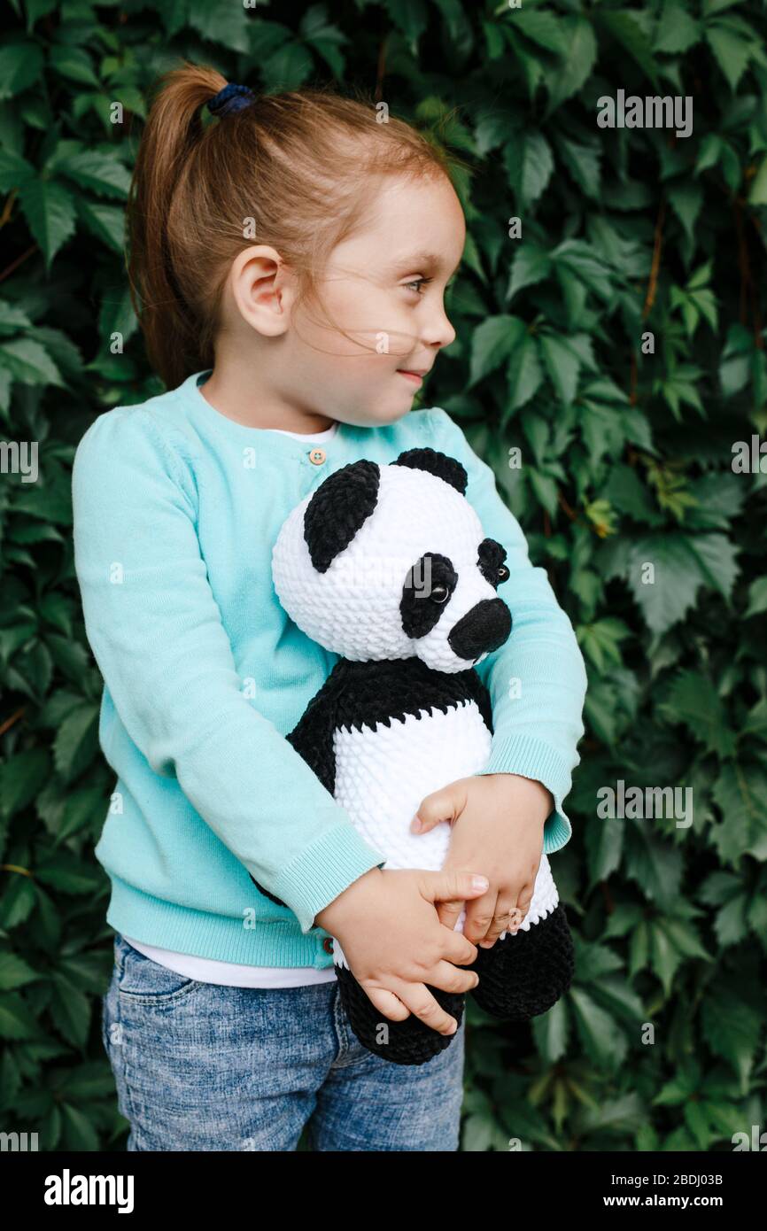 Adorable little girl playing knitted panda toy outdoor Stock Photo - Alamy