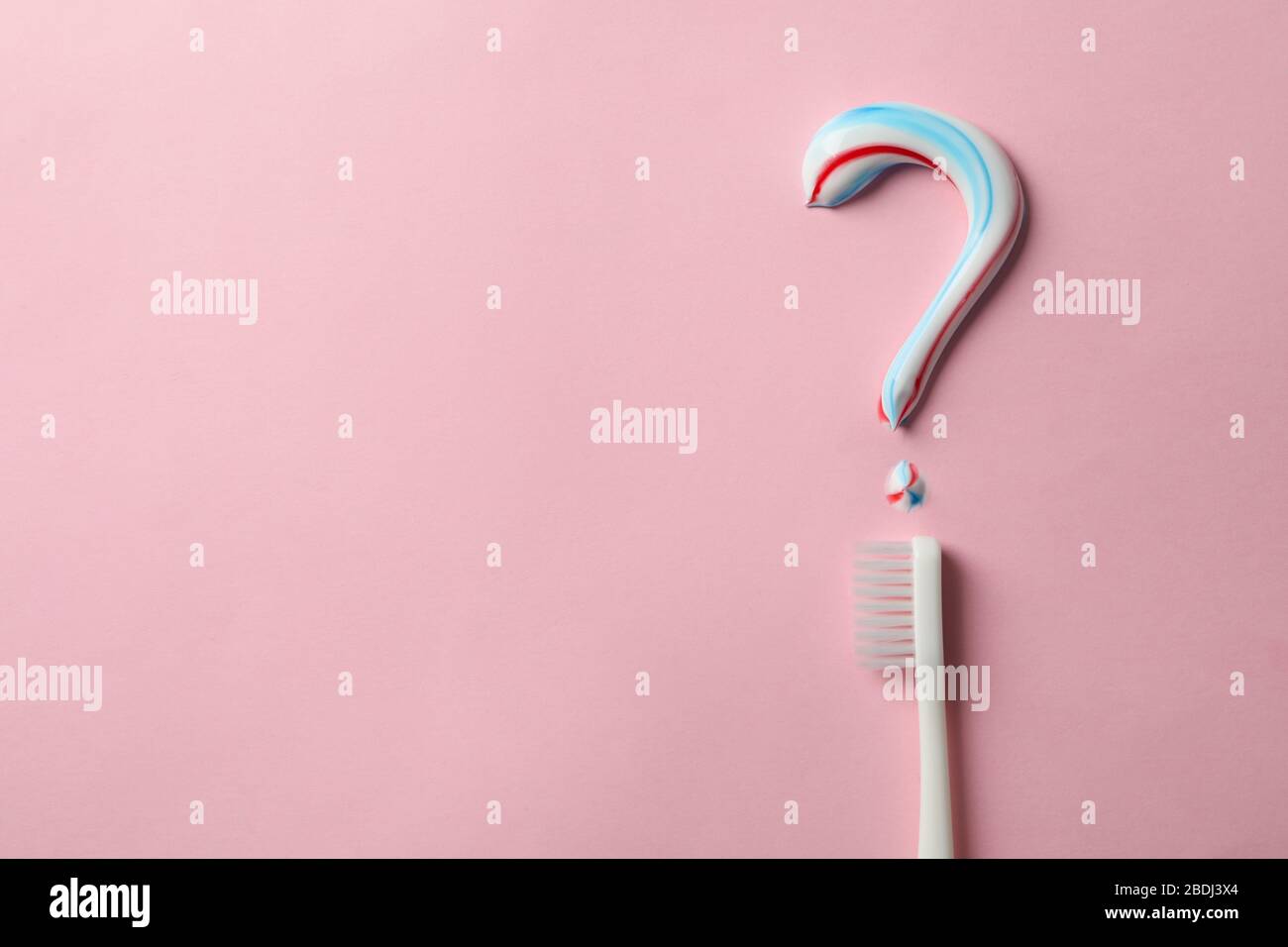 Question mark made of toothpaste and toothbrush on pink background ...