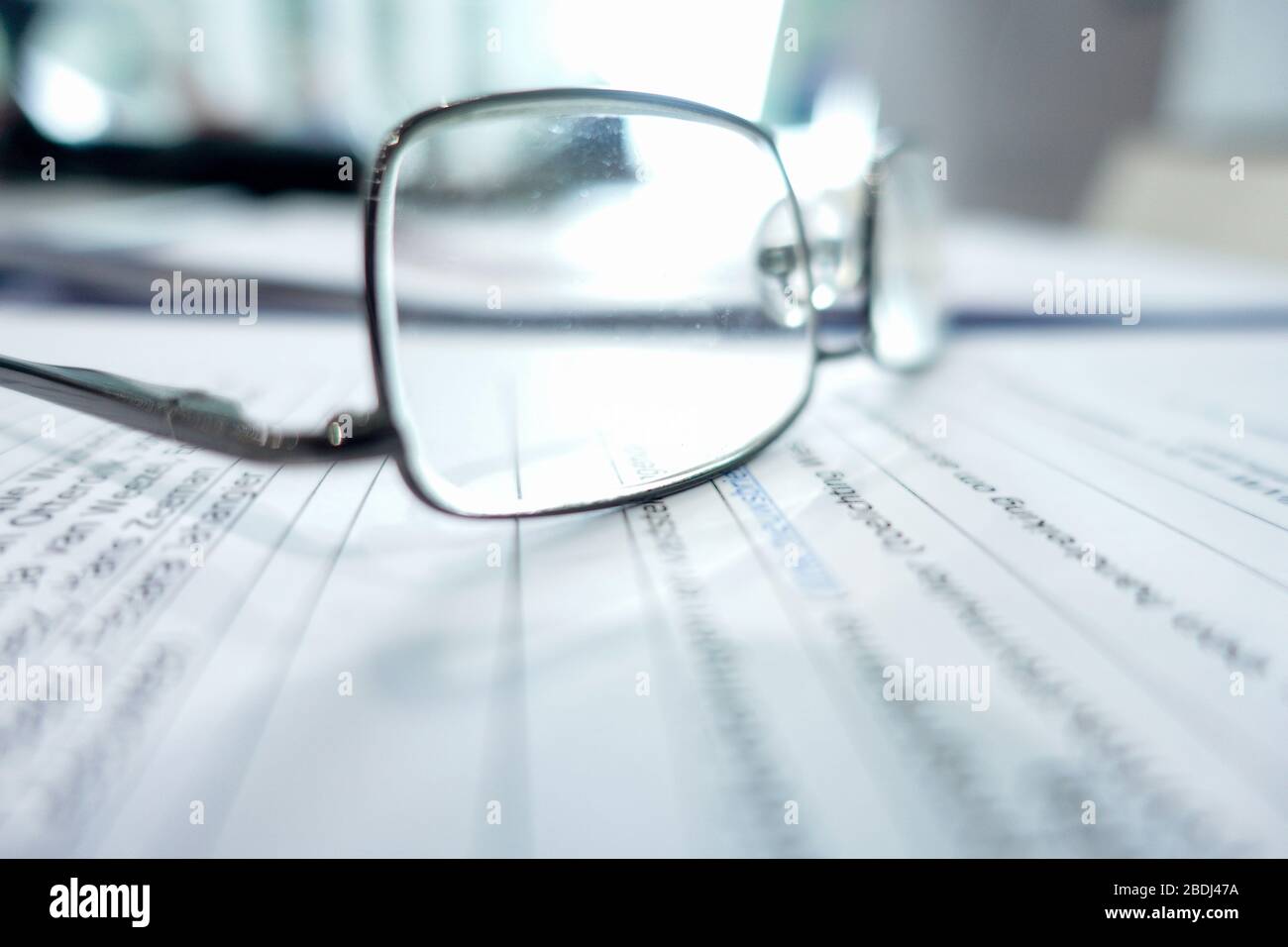 A close up of eye glasses lying on an office table with unrecognisable ...