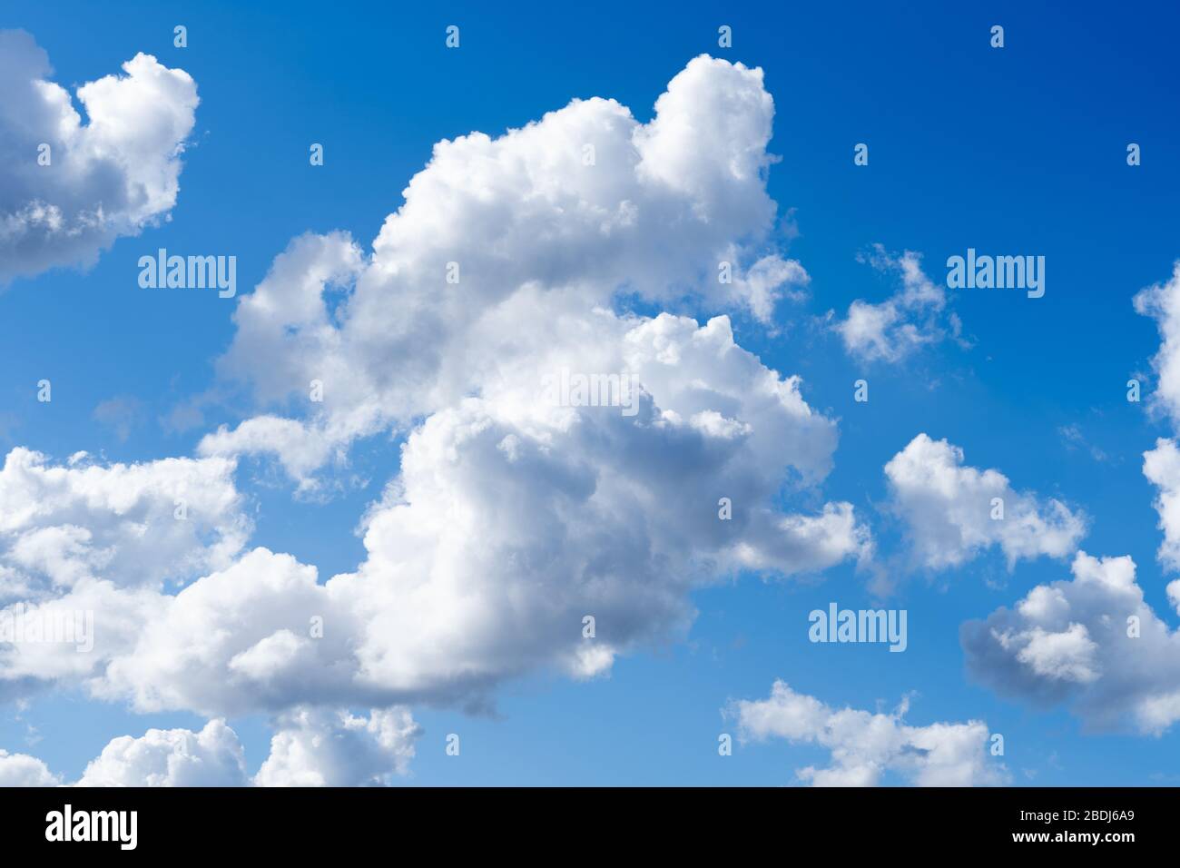 Skyscape with cumulus clouds in white and grey and a clear deep blue ...
