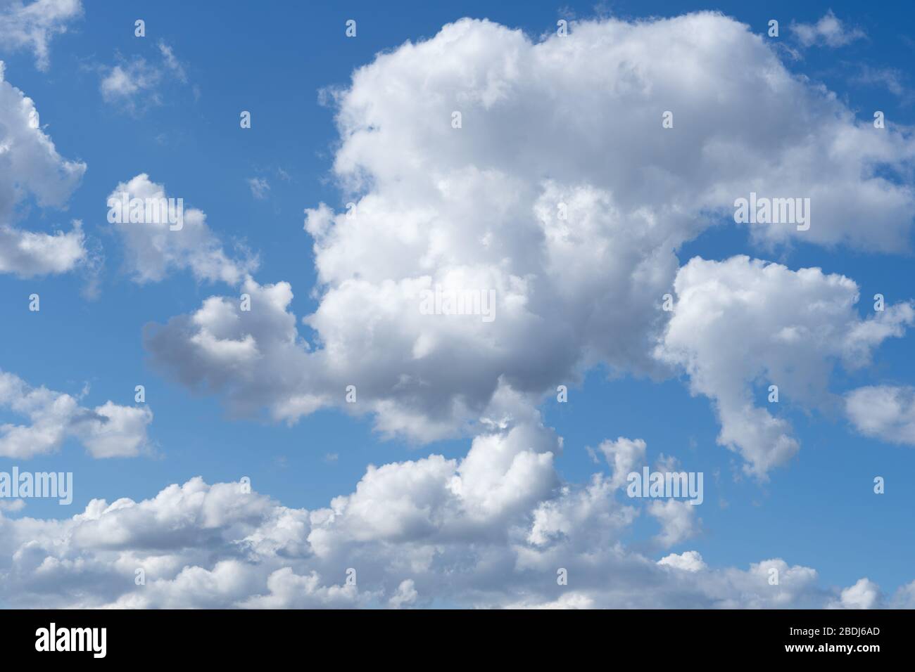 Skyscape with cumulus clouds in white and grey and a clear deep blue ...
