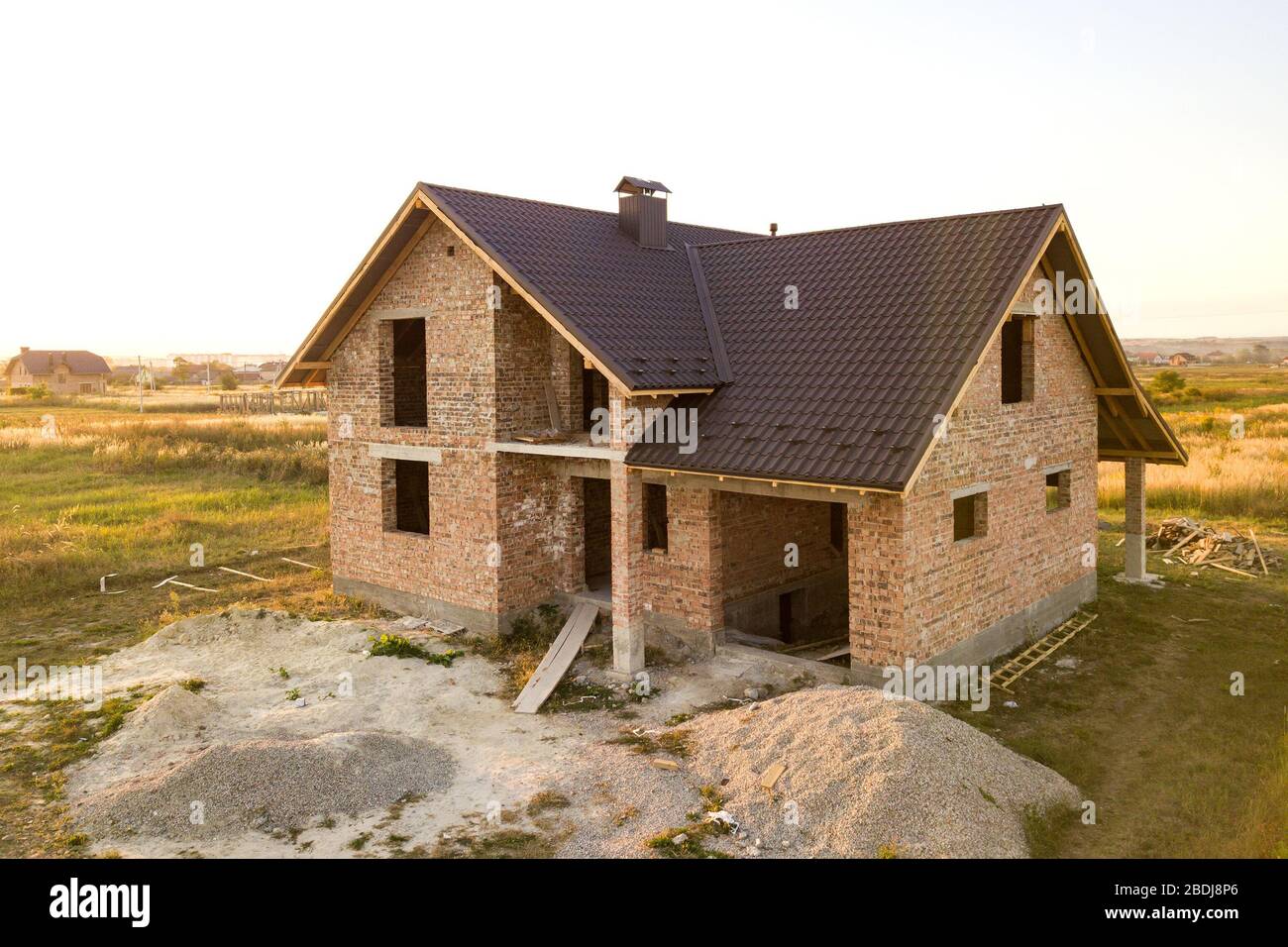Unfinished brick house with wooden roof structure covered with metal ...