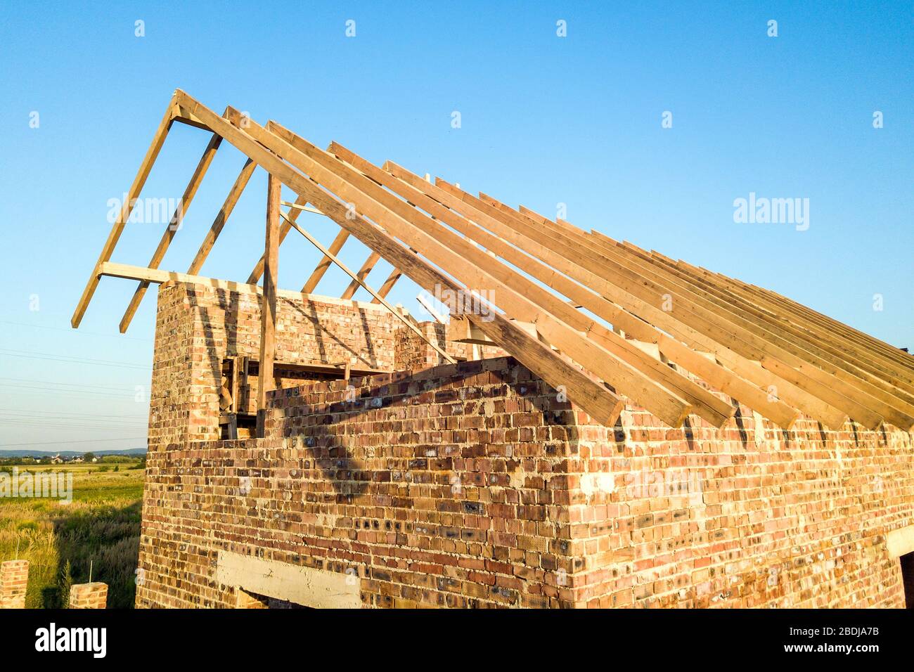 Unfinished brick house with wooden roof structure under construction ...