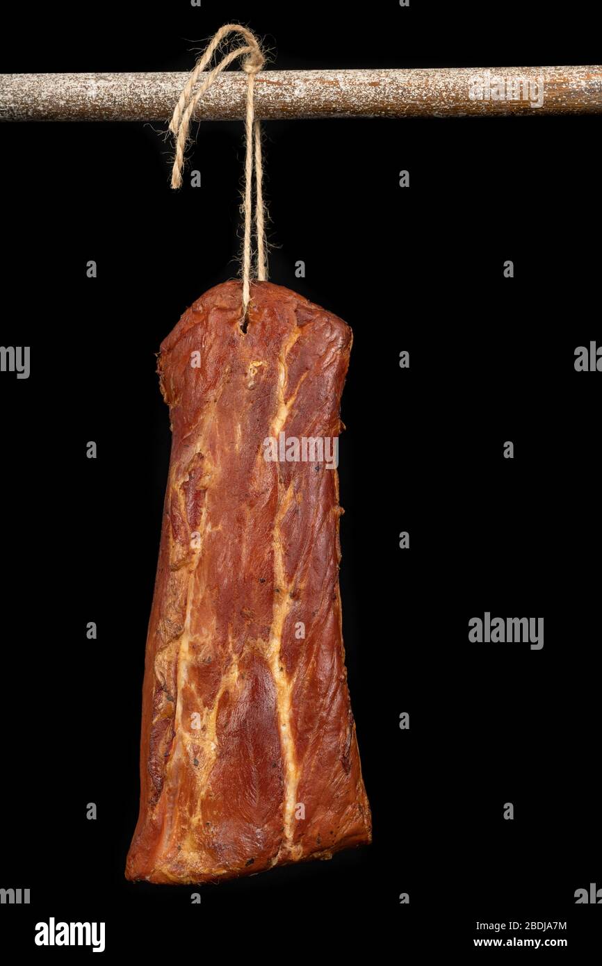 A tasty piece of smoked pork loin hung on a jute string. Stocks in the ...