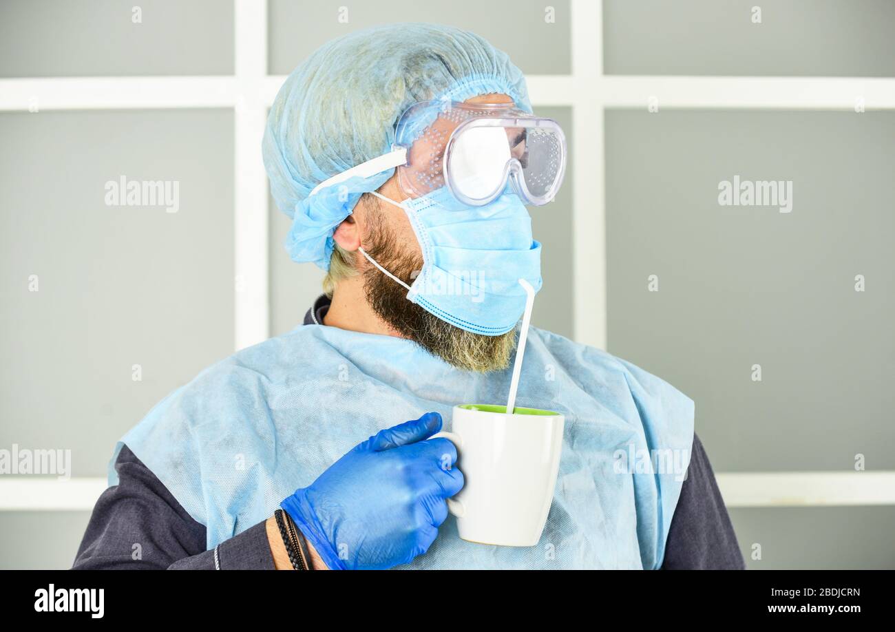 medical mask as corona protection. man drink coffee in respirator ...