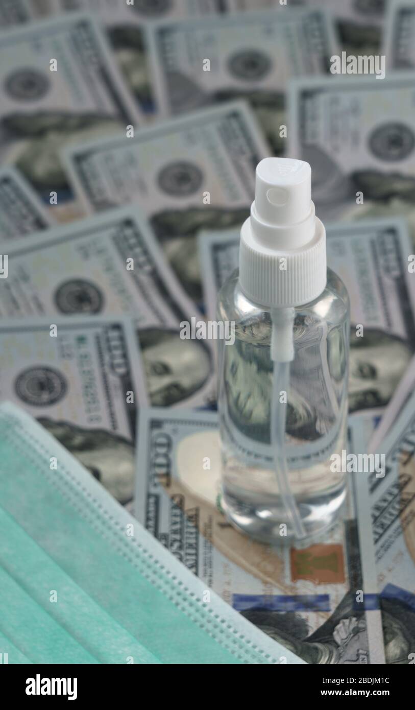 Alcohol spray bottle on top of hundred dollars banknotes and facial ...