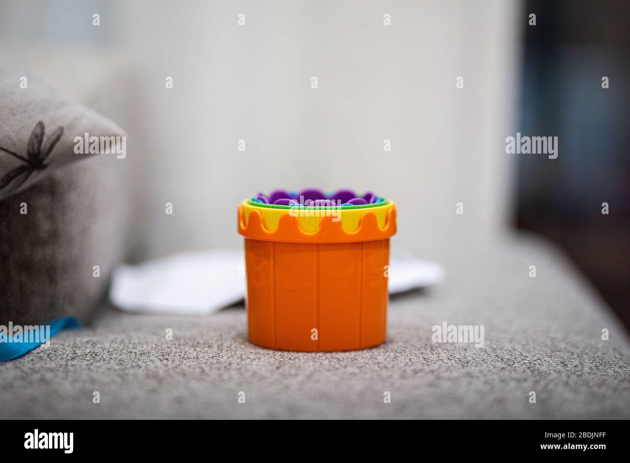 Colorful plastic toy bucket collapsed on a grey sofa Stock Photo - Alamy