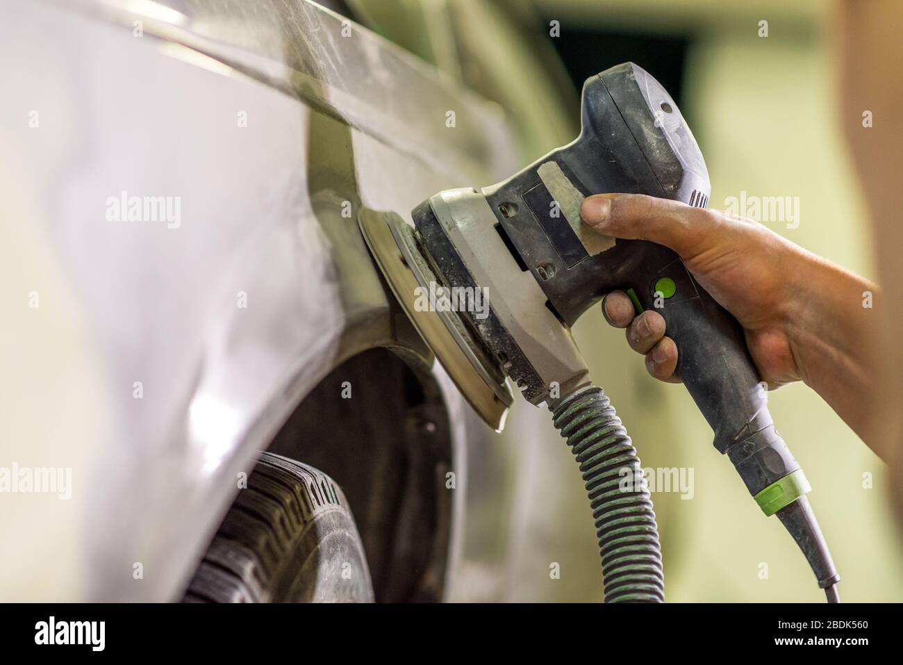 Grinder in the hands of a man who sharpen a car varnish in the car shop ...