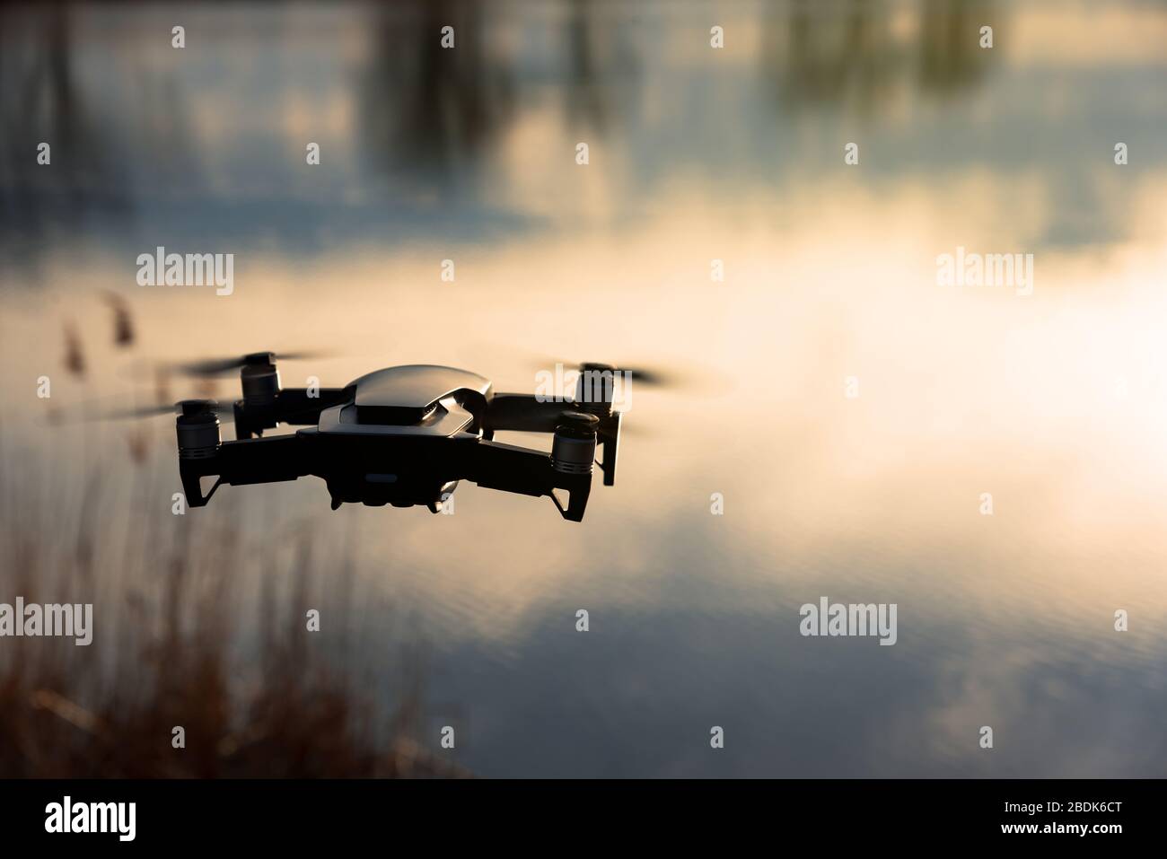 Small modern drone taking picture of lake at sunset Stock Photo - Alamy