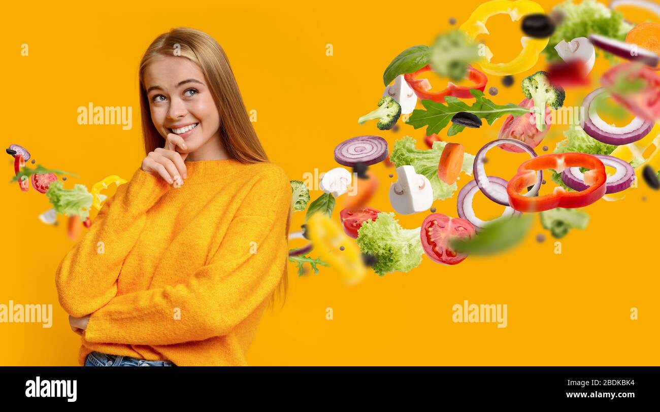 Weight loss. Lovely woman and flying vegetables on orange background ...