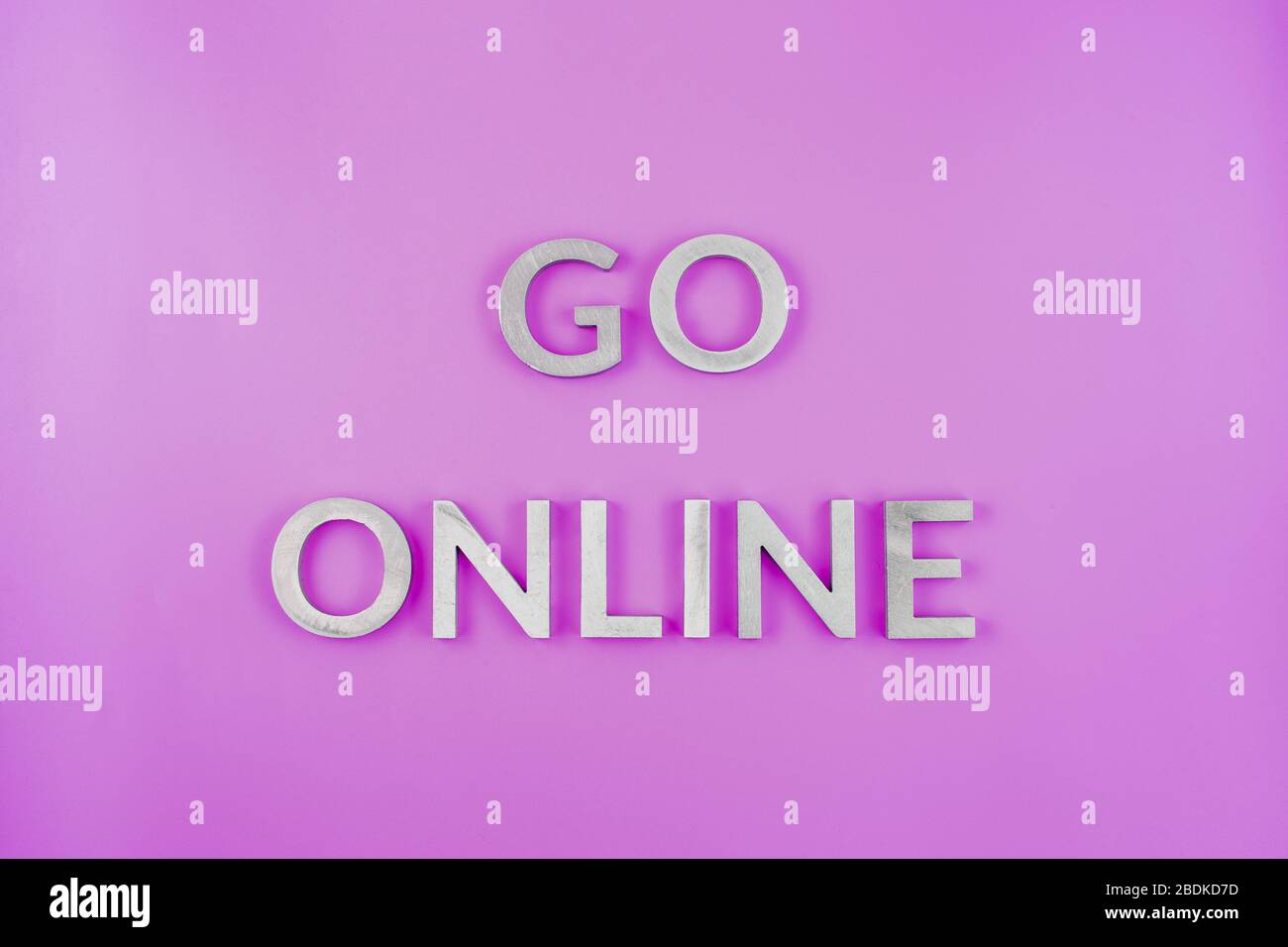 the words go online laid with brushed aluminium letters on flat pink ...