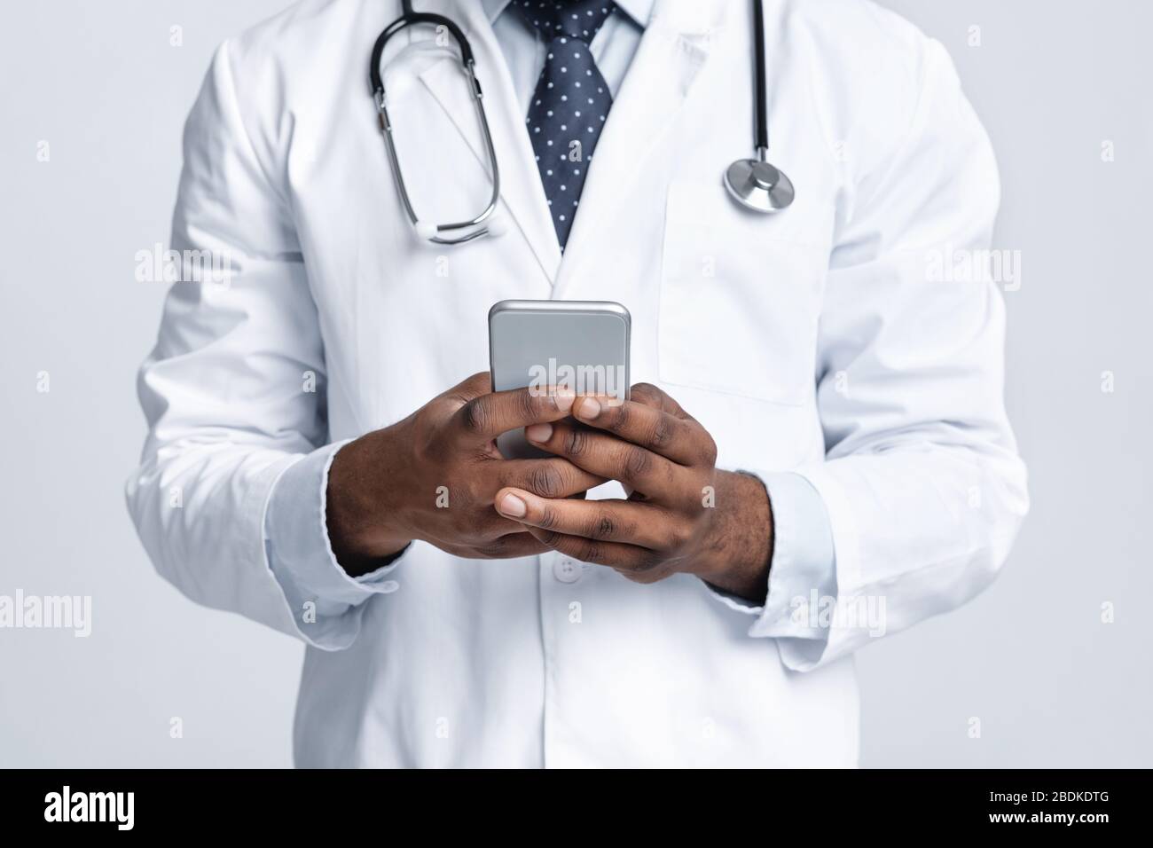 Cropped of african doctor holding mobile phone, white background Stock ...