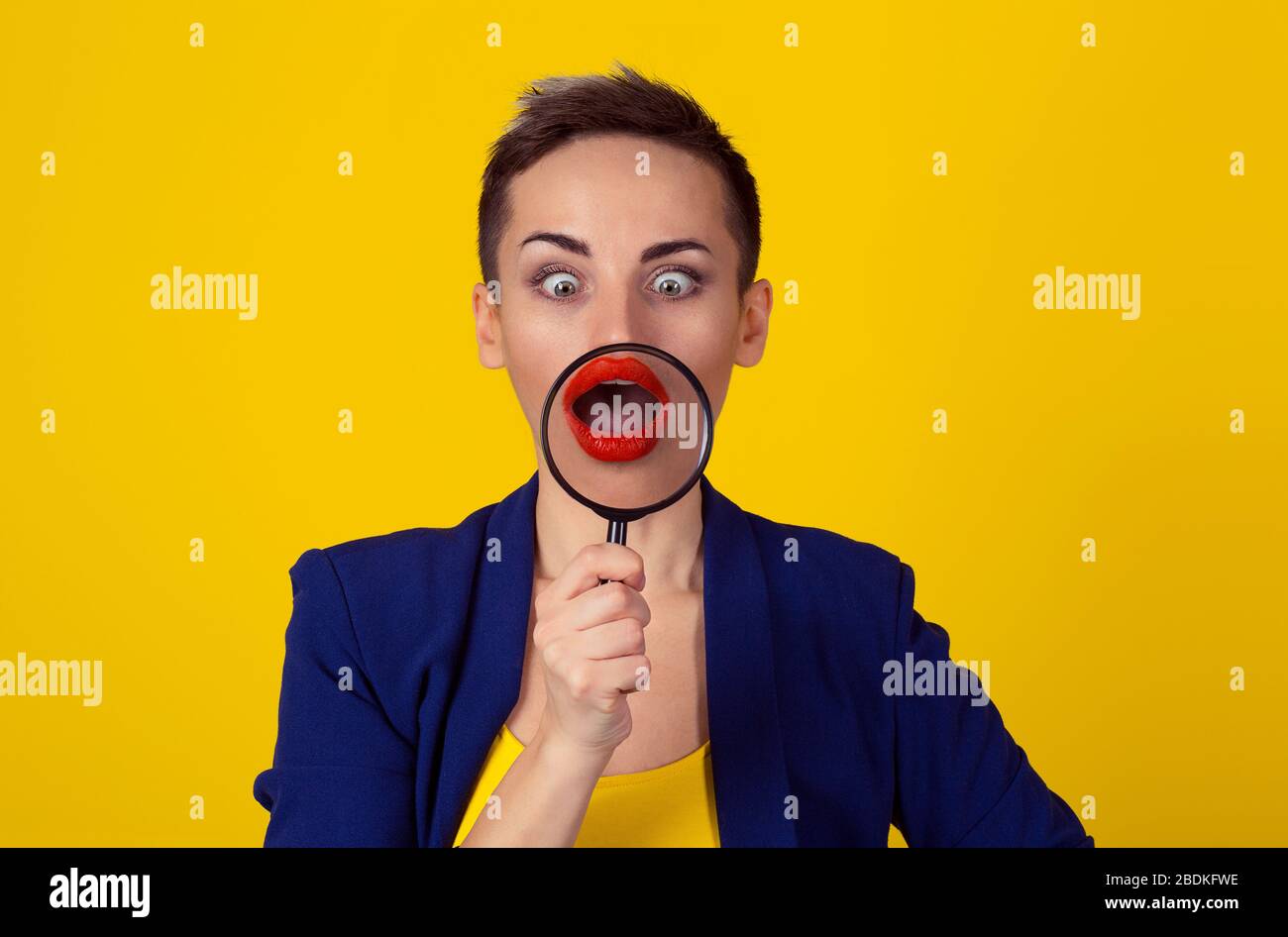 Amazed surprised woman looking down with magnifying glass on mouth ...