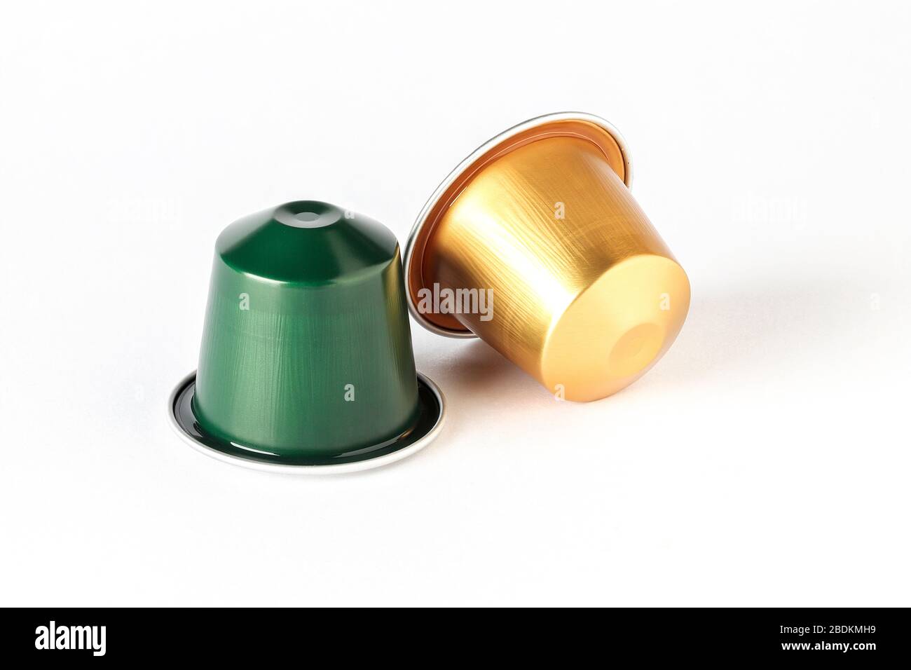 horizontal view of two gold and green color espresso coffee capsules ...