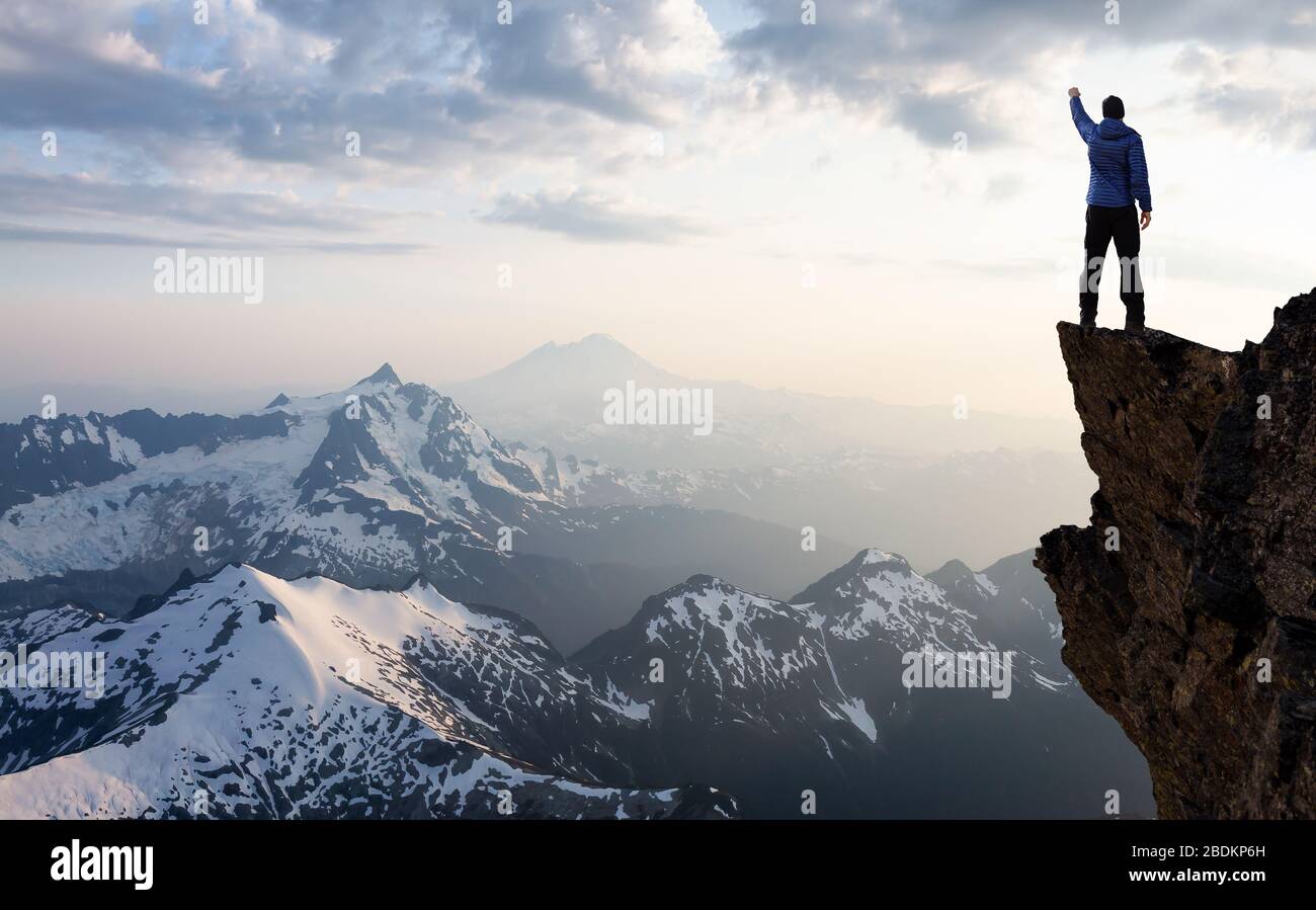 Adventurous Man Hiker With Hands Up on top of a Steep Rocky Cliff Stock ...