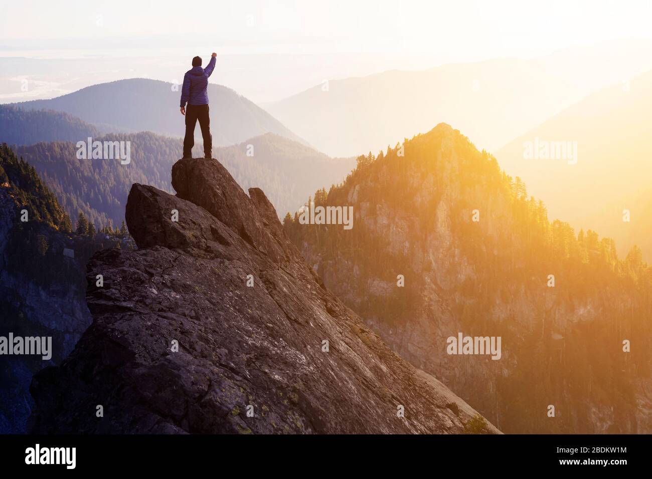 Adventurous Man Hiker With Hands Up on top of a Steep Rocky Cliff Stock ...